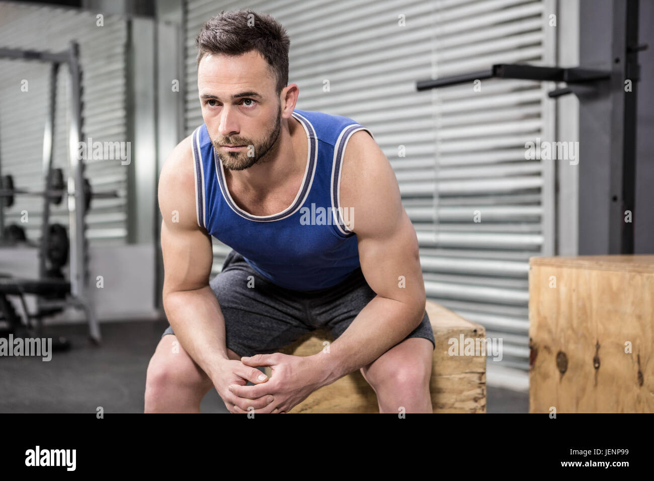 Muscular man sitting on wooden block Stock Photo - Alamy