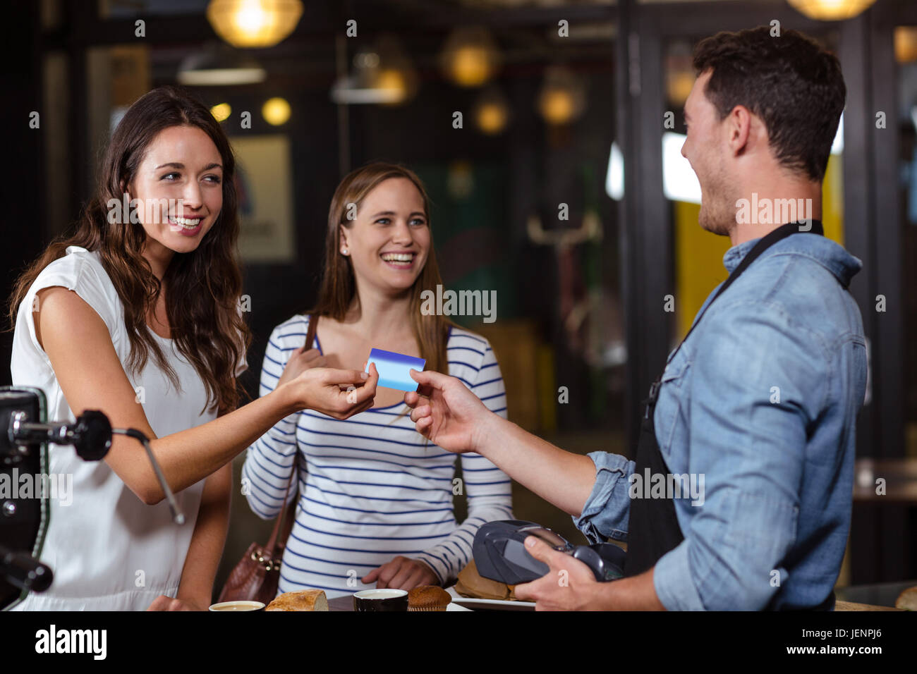 Smiling clients paying with card Stock Photo - Alamy
