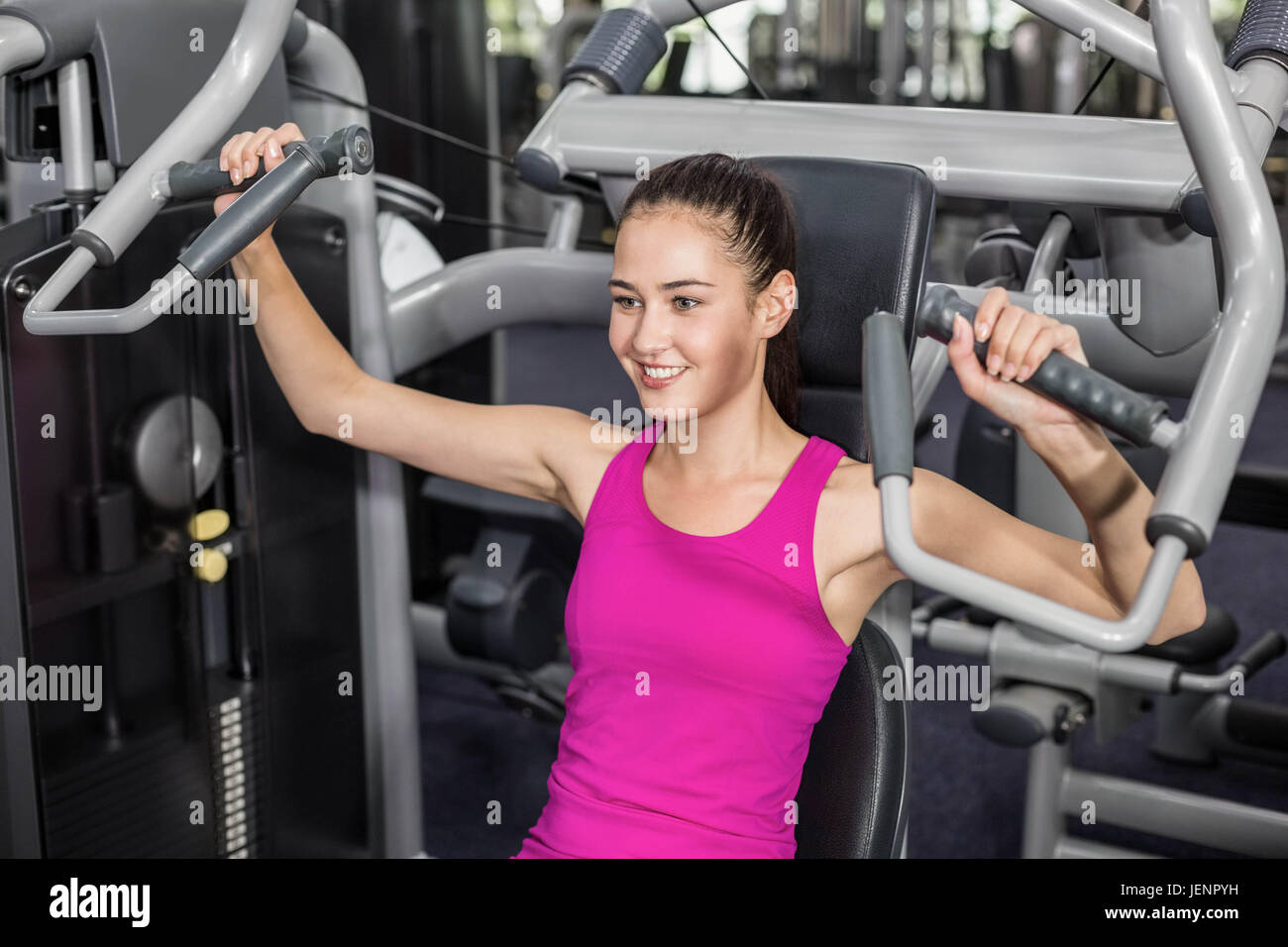 Fit woman using weight machine Stock Photo - Alamy