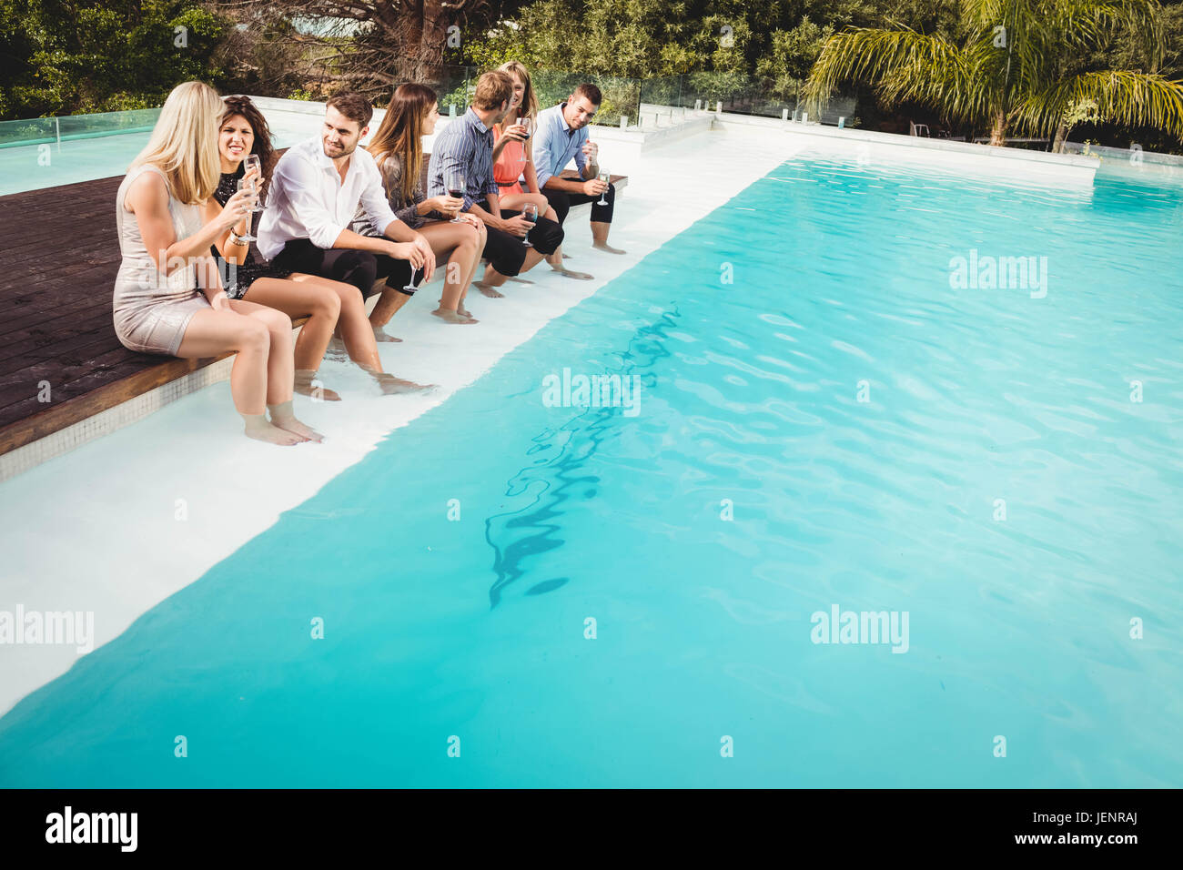 Young people sitting by swimming pool Stock Photo - Alamy