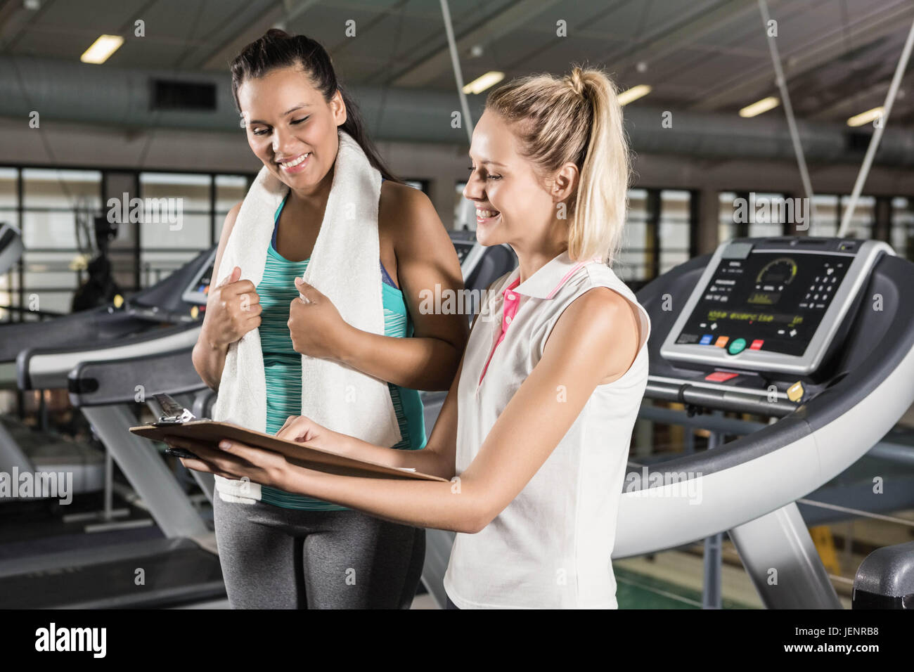 Smiling trainer showing clipboard to woman Stock Photo - Alamy