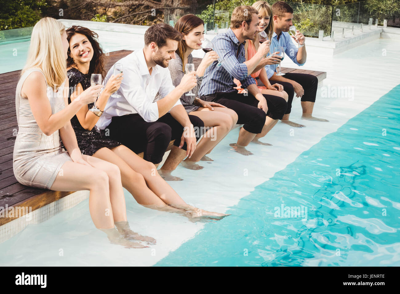 Young people sitting by swimming pool Stock Photo - Alamy