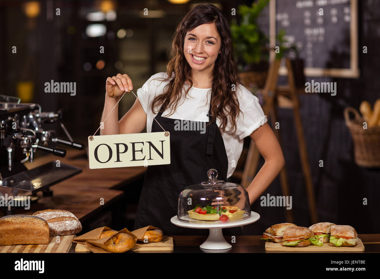 Pretty waitress holding a open sign Stock Photo - Alamy