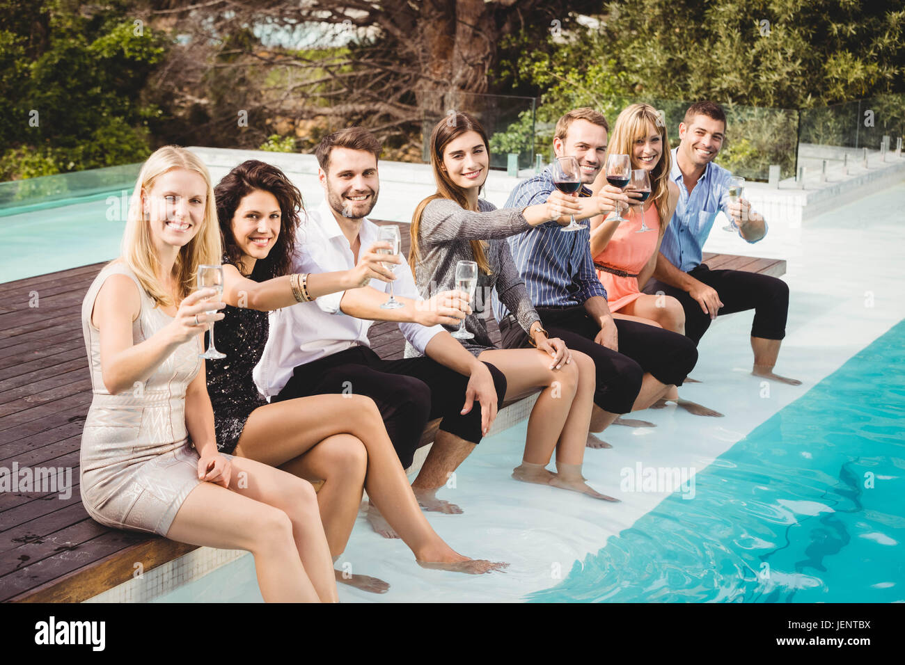 Young people sitting by swimming pool Stock Photo - Alamy