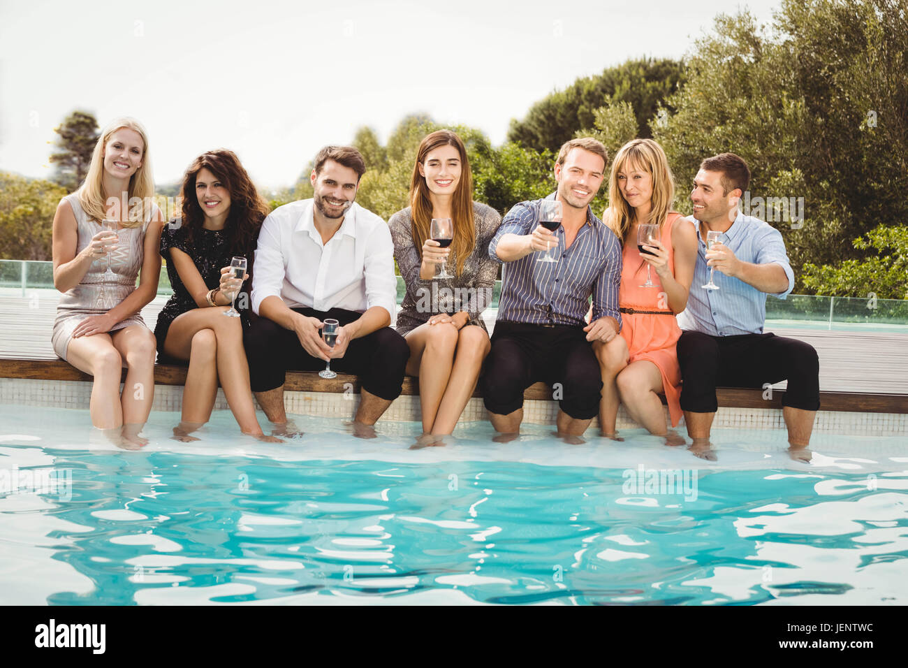 Young people sitting by swimming pool Stock Photo - Alamy
