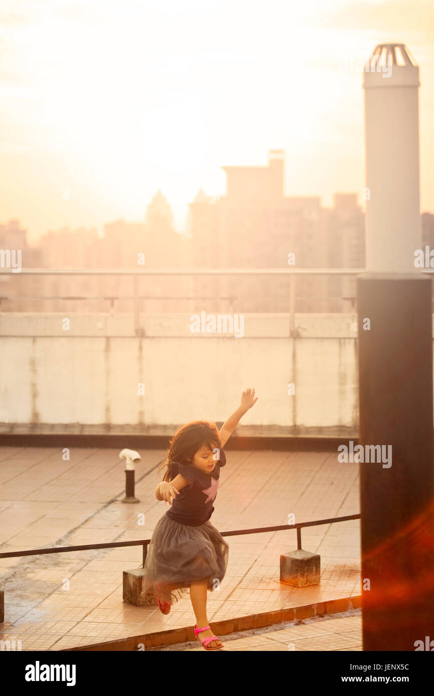 Girl running on roof, cityscape at sunset on background Stock Photo - Alamy