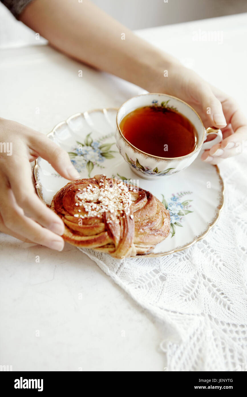 Hands with tea and bun Stock Photo - Alamy