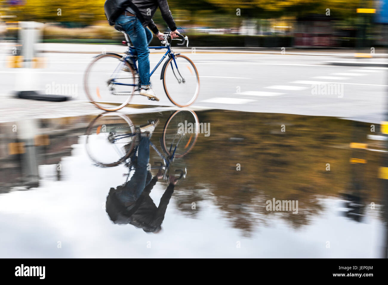 Person cycling along puddle Stock Photo - Alamy