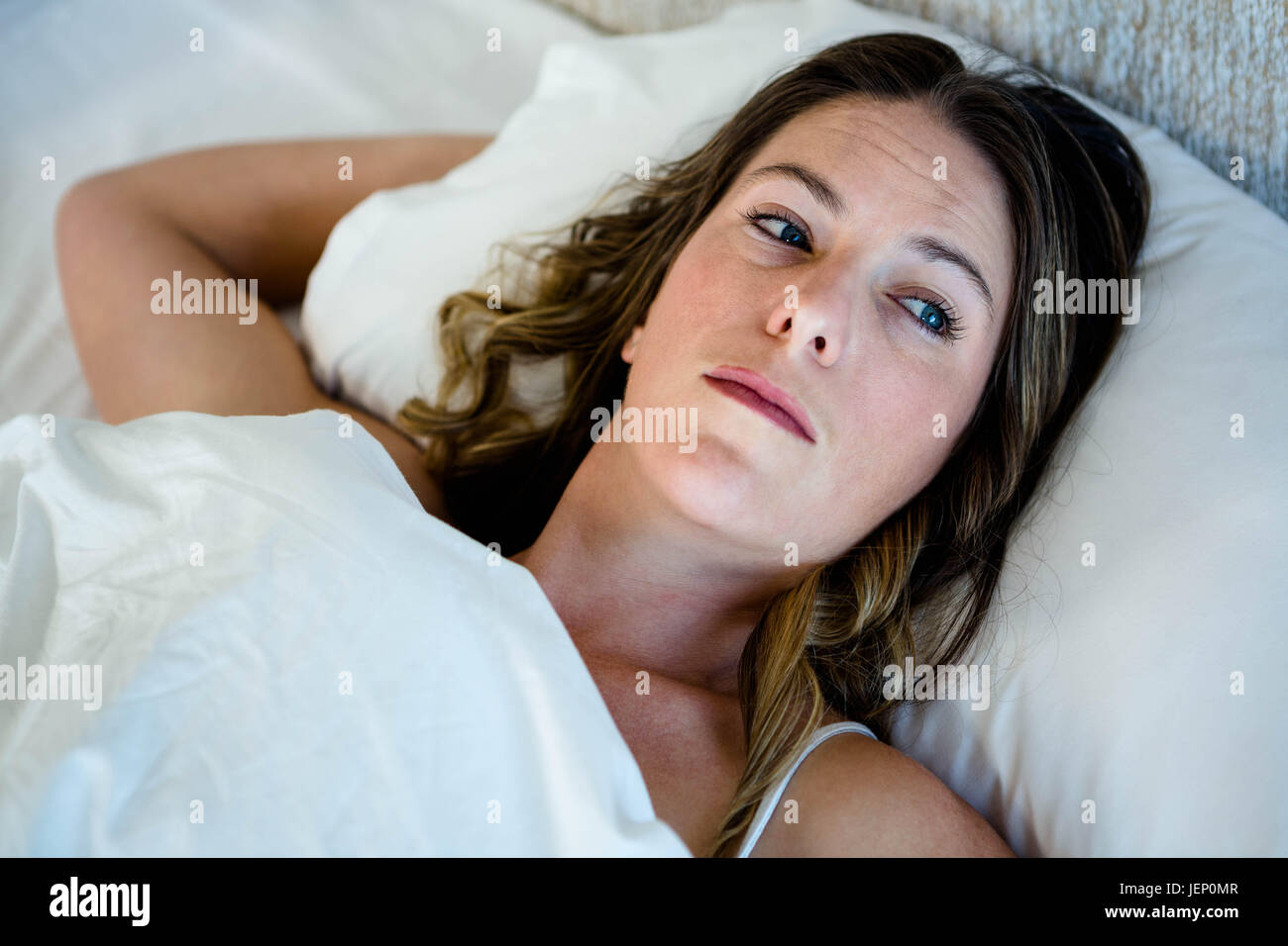 tired woman lying in bed staring into space Stock Photo - Alamy
