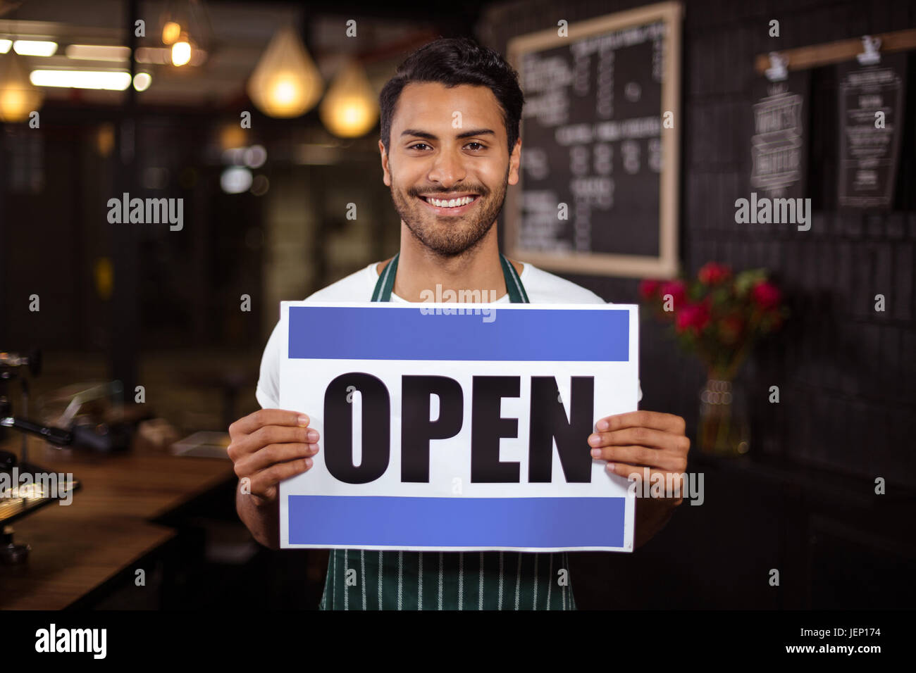 Smiling barista holding open sign Stock Photo - Alamy