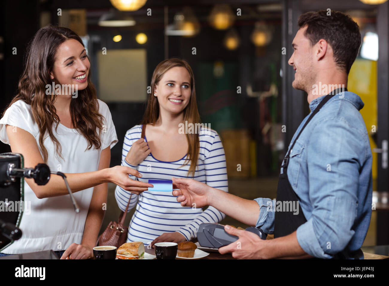 Smiling clients paying with card Stock Photo - Alamy