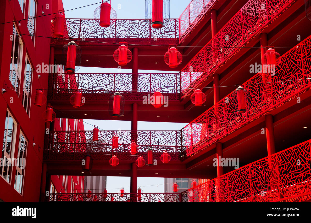 A red building exterior and red lanterns hanging from wires near the ...