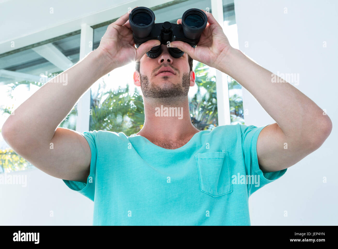 Hipster man looking through binoculars Stock Photo - Alamy