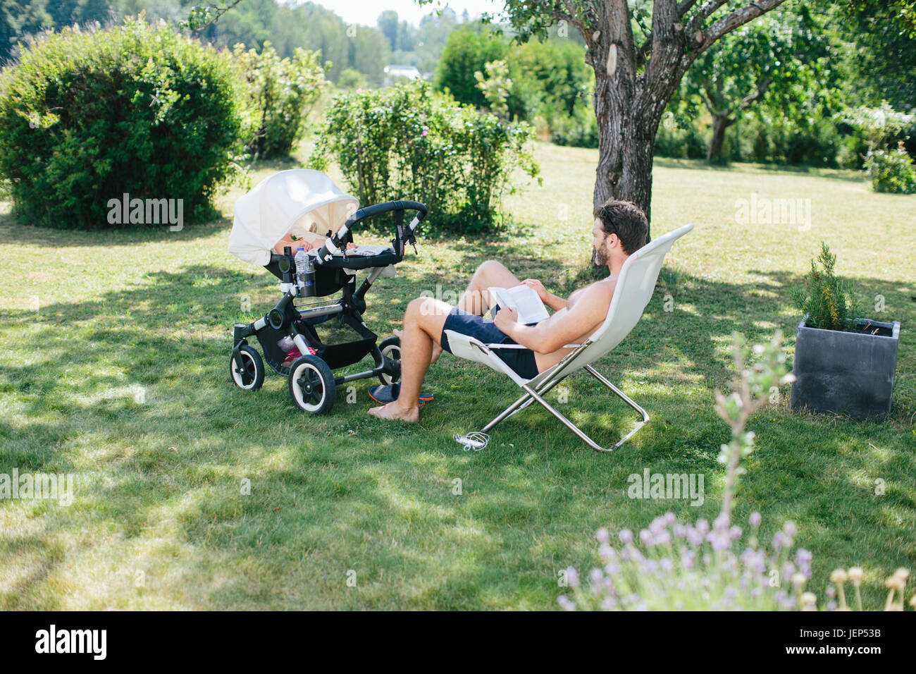 Father in garden with child in buggy Stock Photo - Alamy