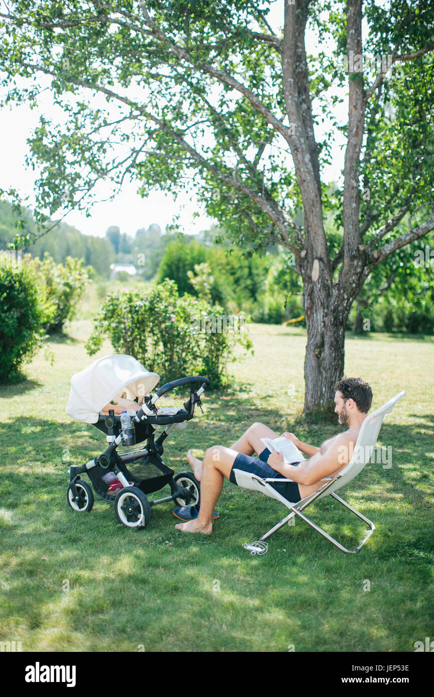 Father in garden with child in buggy Stock Photo - Alamy