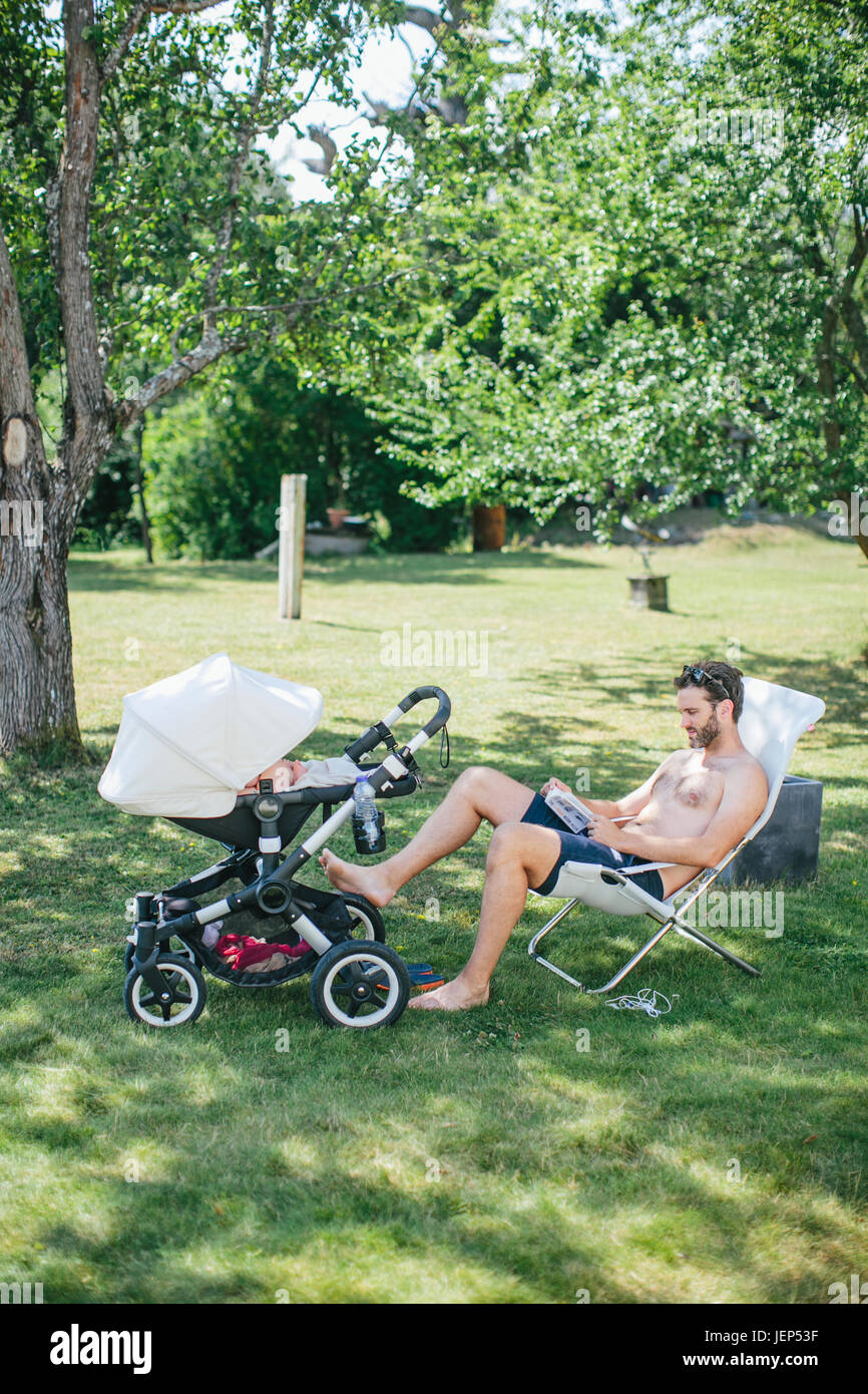Father in garden with child in buggy Stock Photo - Alamy
