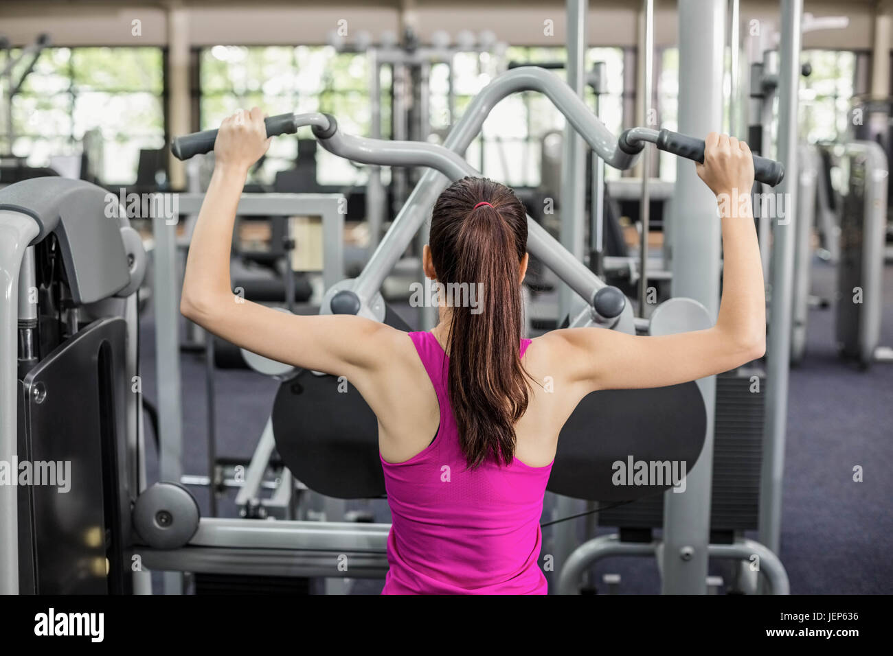 Fit woman using weight machine Stock Photo - Alamy