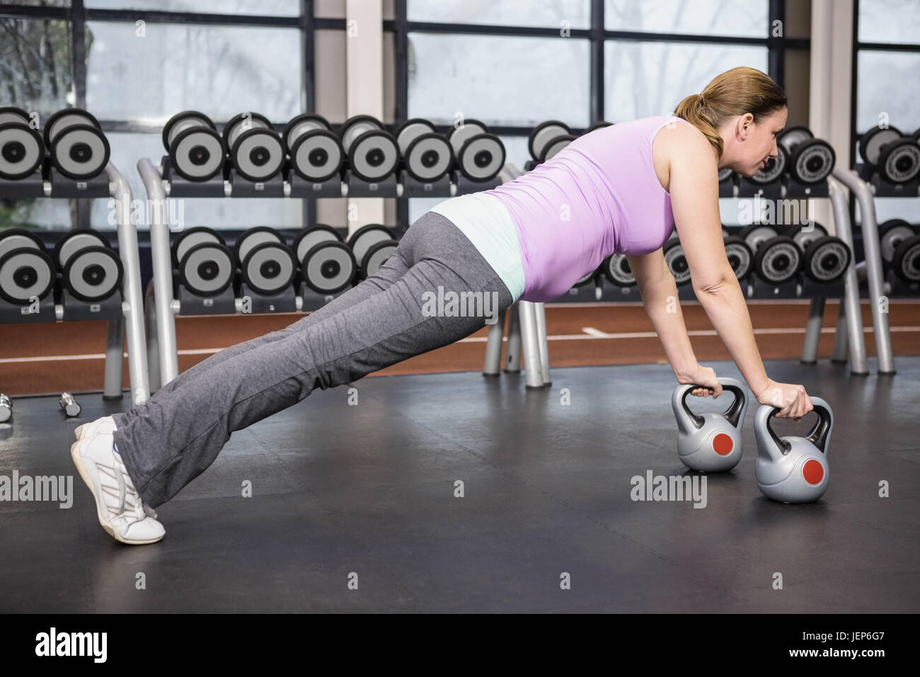 Determined woman planking with kettlebells Stock Photo - Alamy