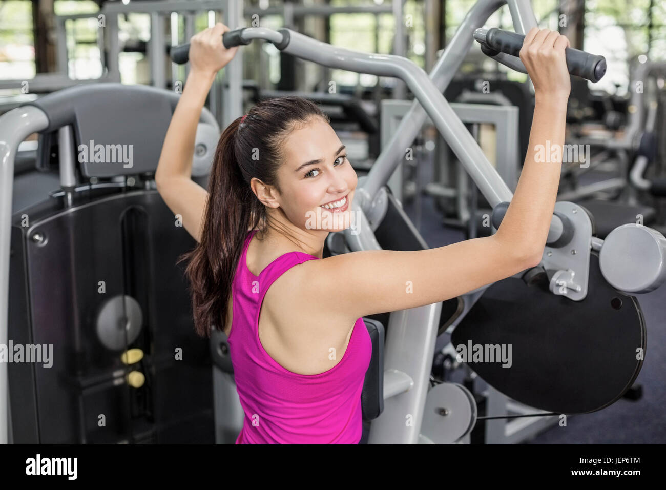 Fit woman using weight machine Stock Photo - Alamy