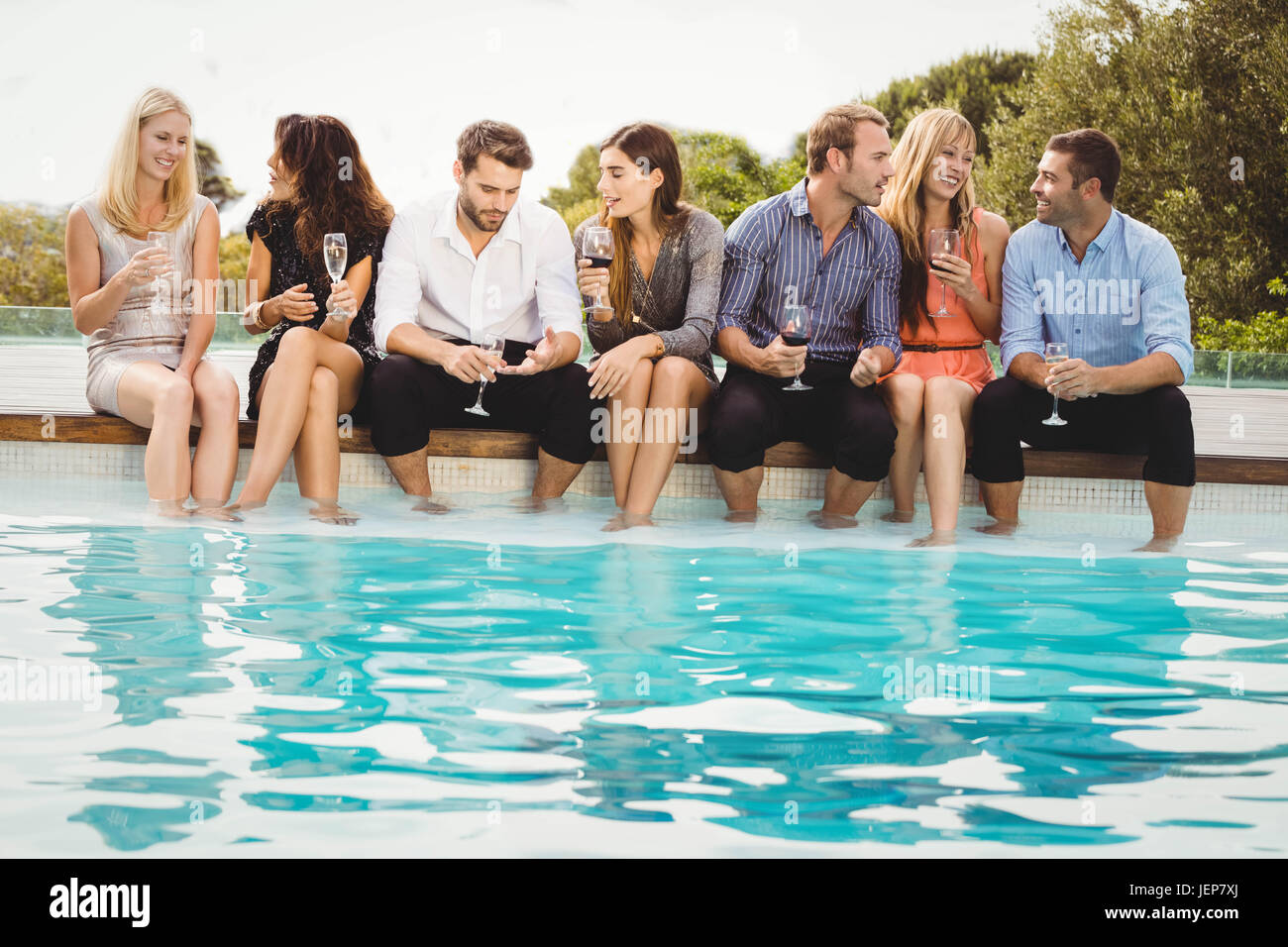 Young people sitting by swimming pool Stock Photo - Alamy