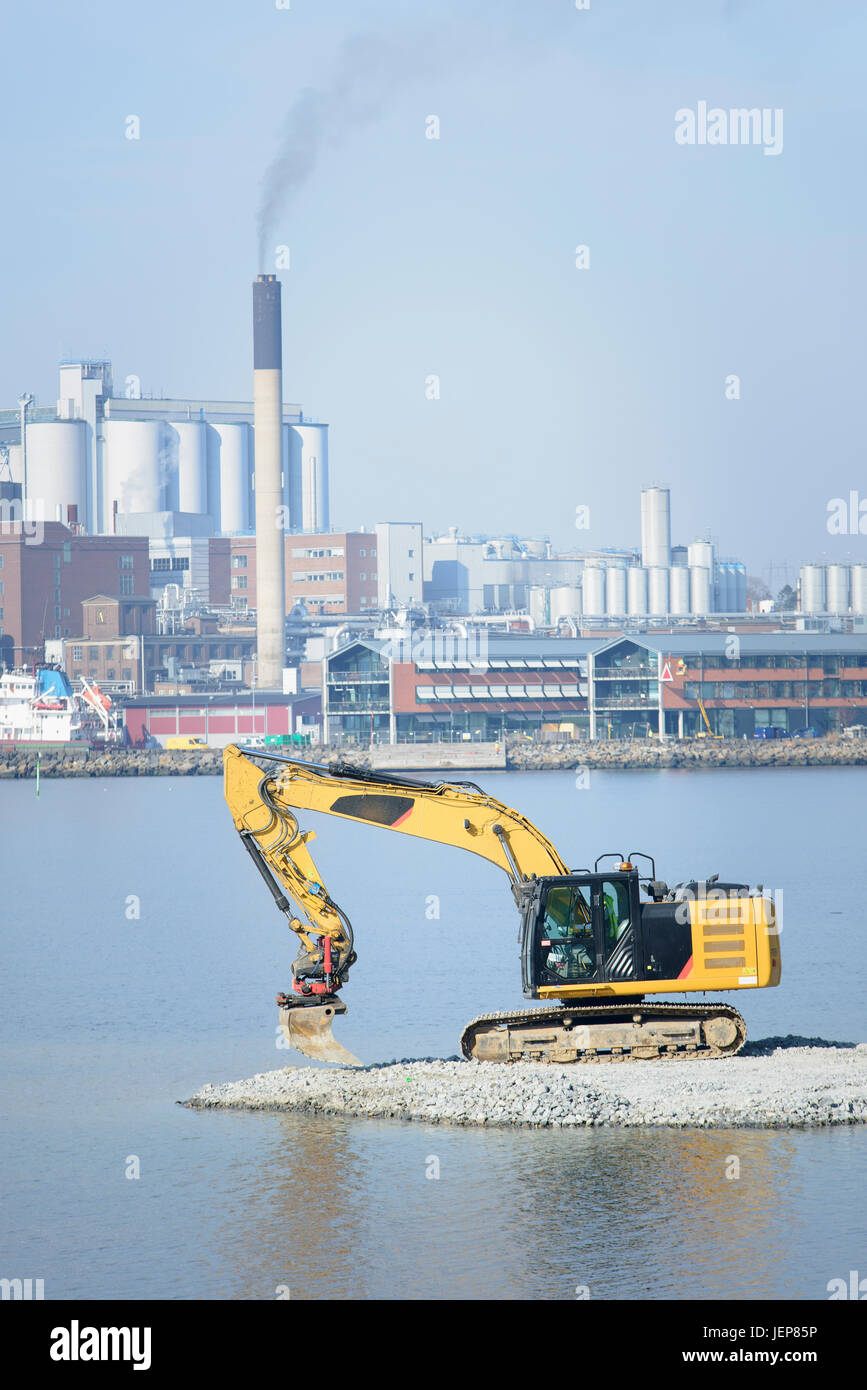 Digger, factory on background Stock Photo - Alamy