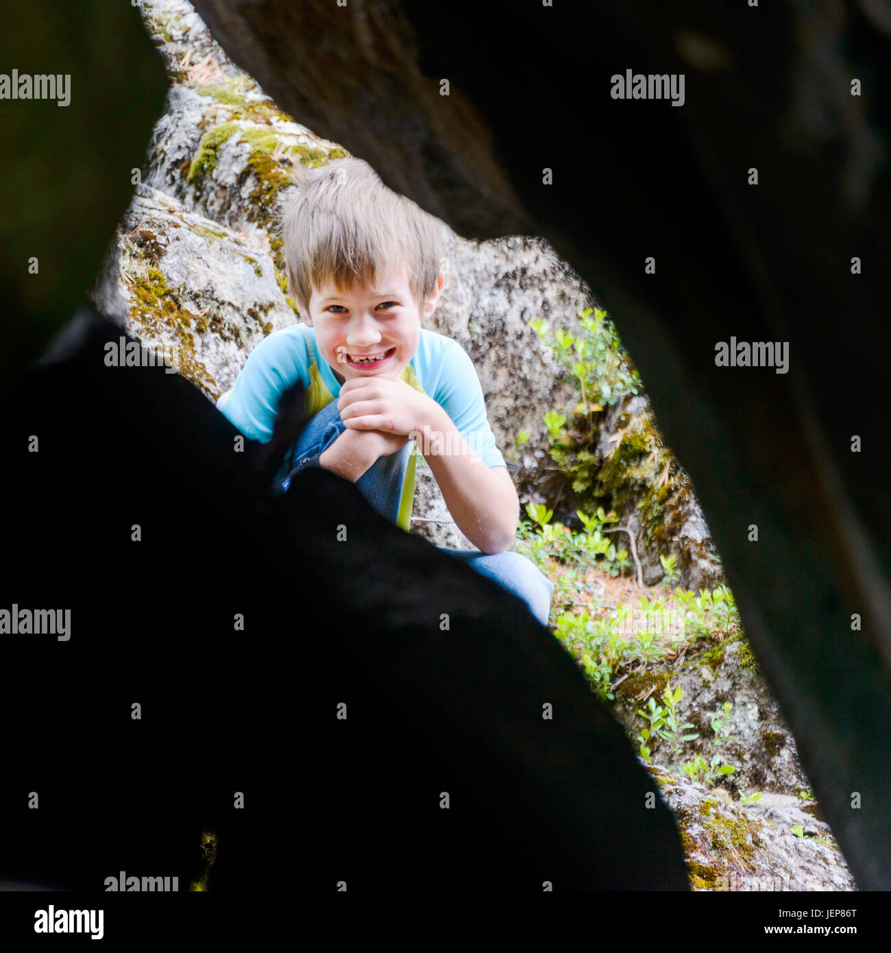 Boy looking through rock hole Stock Photo - Alamy