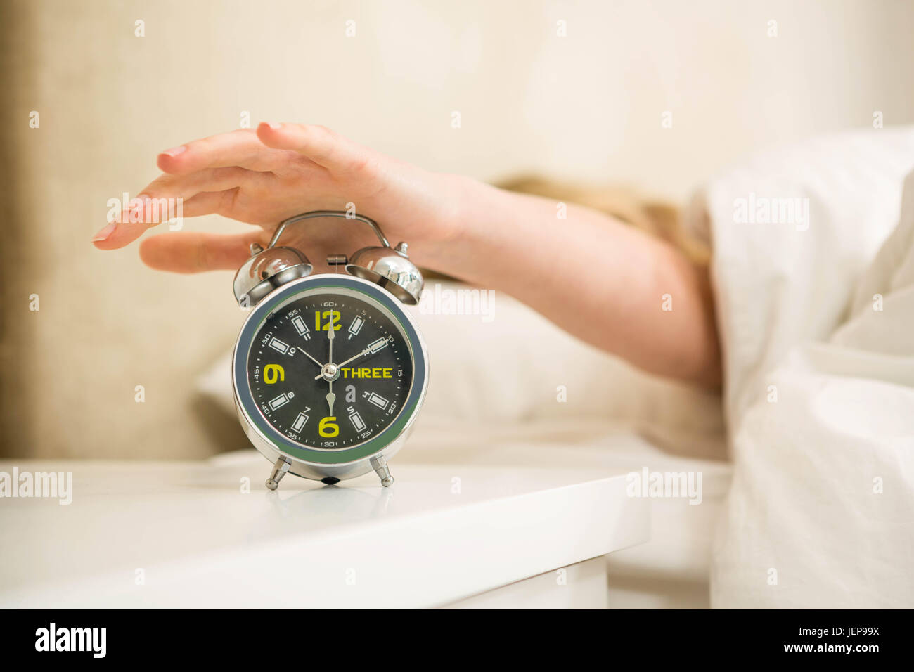 Pretty woman shutting off her alarm clock Stock Photo - Alamy