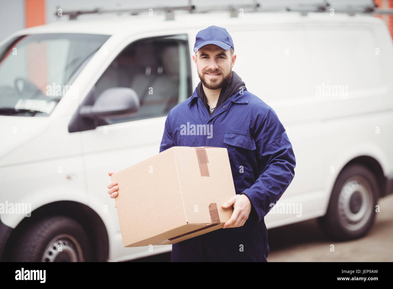 Delivery man holding box Stock Photo - Alamy