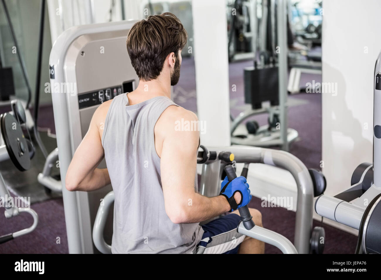Focused man using weights machine for arms Stock Photo - Alamy