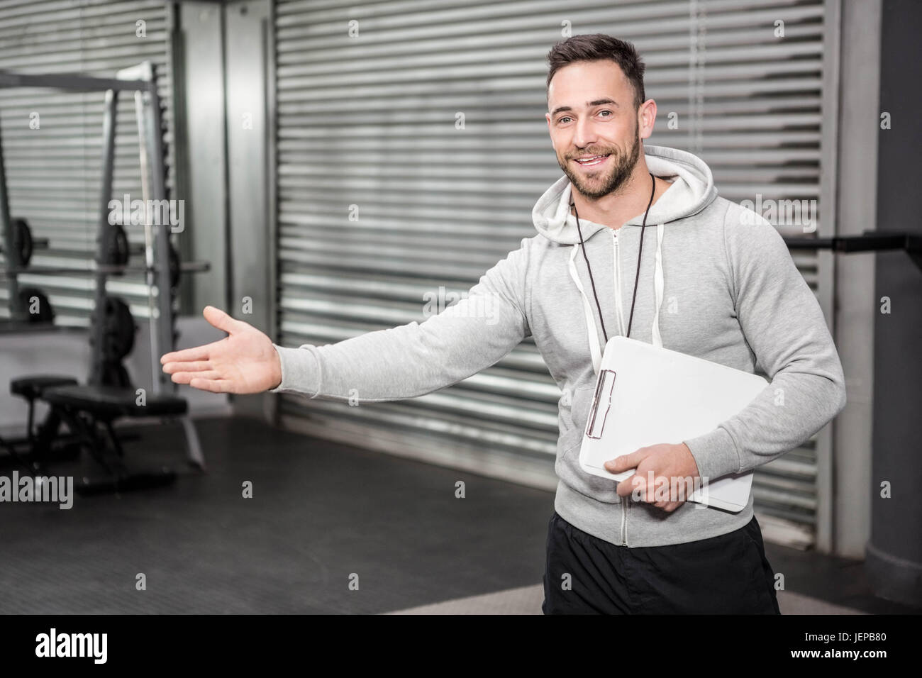 Smiling trainer showing gym to camera Stock Photo - Alamy