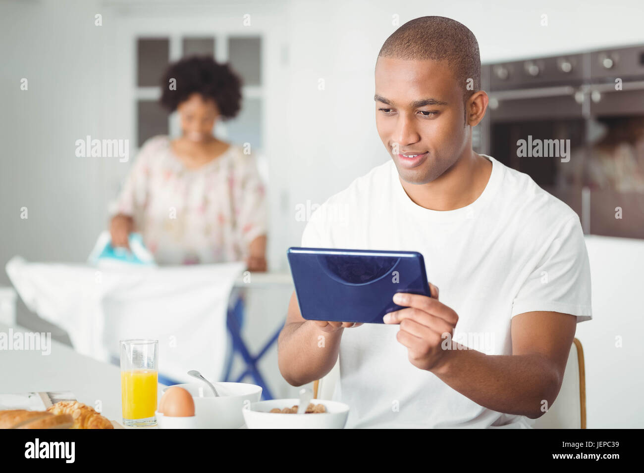 Young man using tablet in kitchen Stock Photo - Alamy
