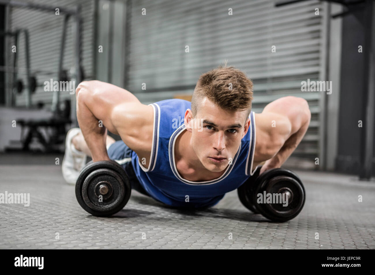 Muscular man doing push up with dumbbells Stock Photo - Alamy