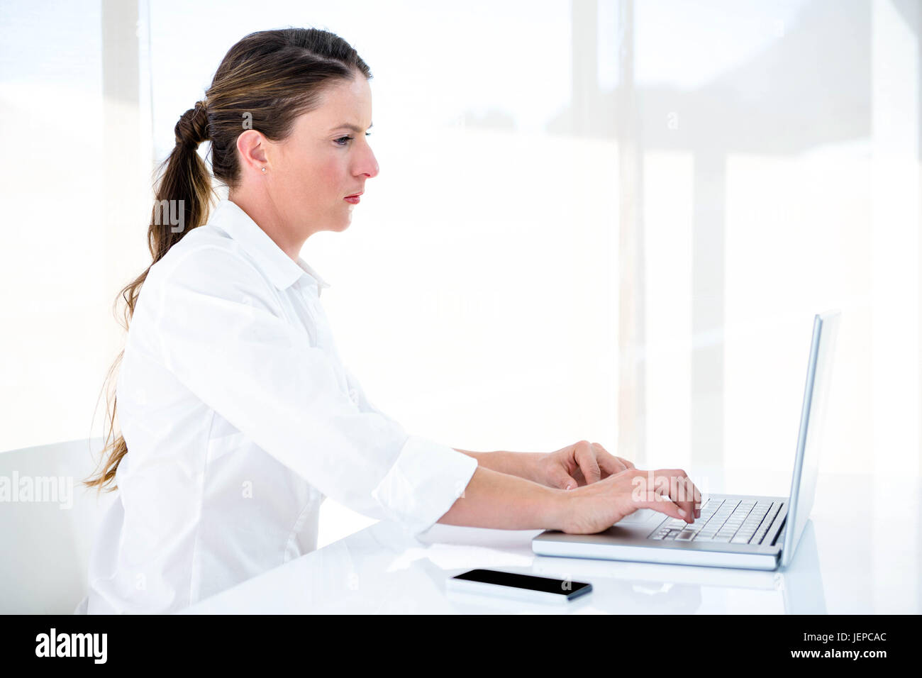 serious business woman typing on her laptop Stock Photo - Alamy