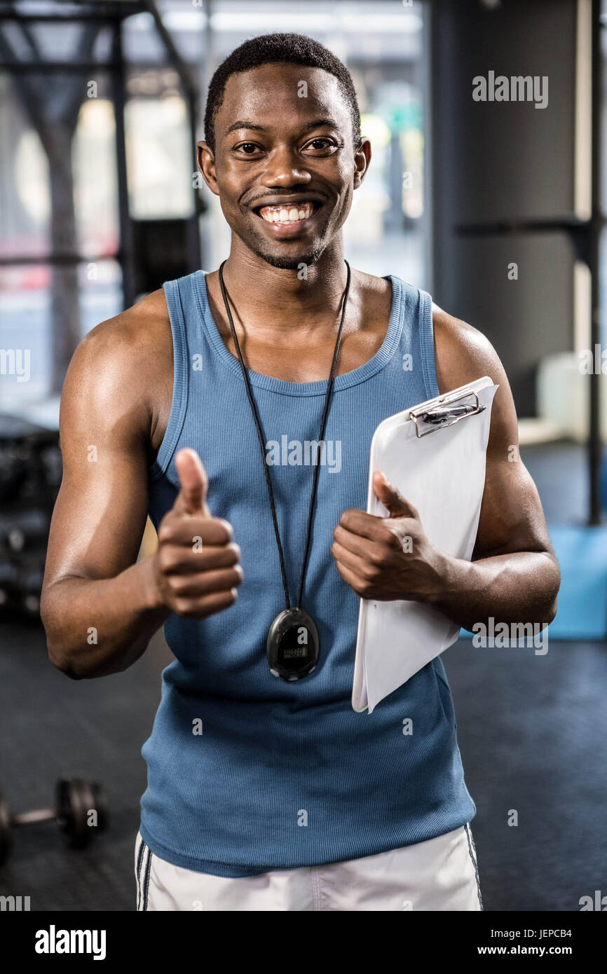 Smiling trainer showing thumbs up Stock Photo - Alamy