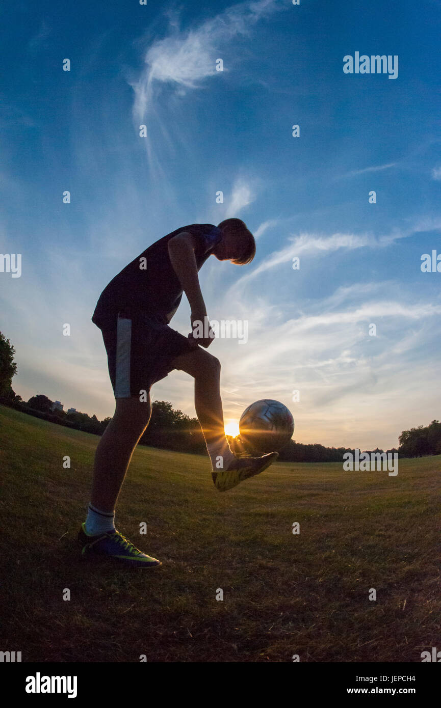 a young boy playing football and practicing his football skills and ...