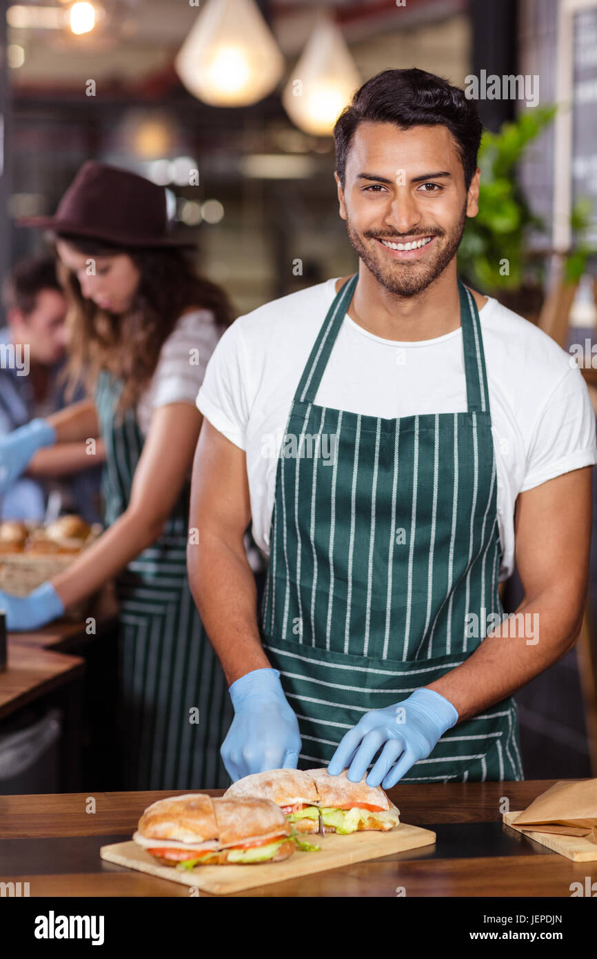 Smiling barista cutting sandwich Stock Photo - Alamy