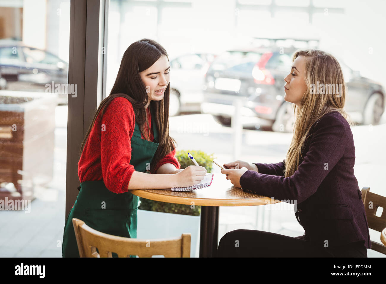 Cute blonde girl ordering from her friend Stock Photo - Alamy