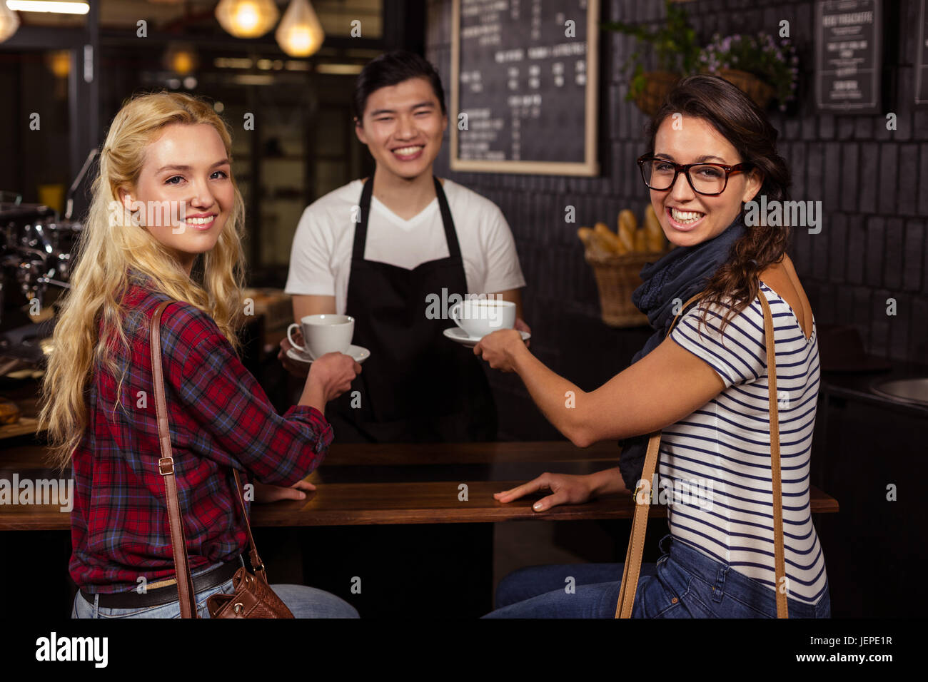 Smiling waiter serving a coffee to customers Stock Photo - Alamy