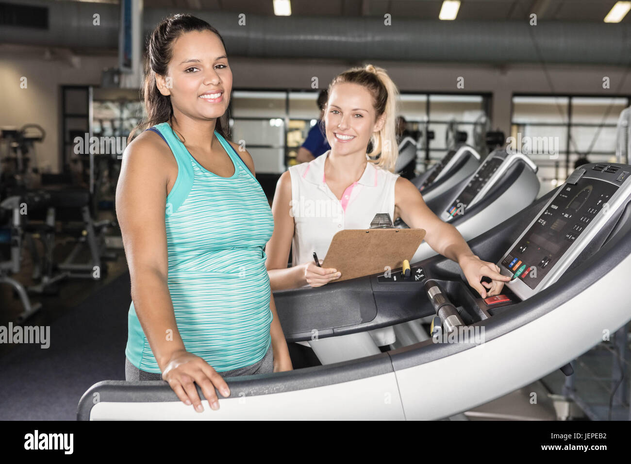 Portrait of woman on treadmill and trainer Stock Photo - Alamy