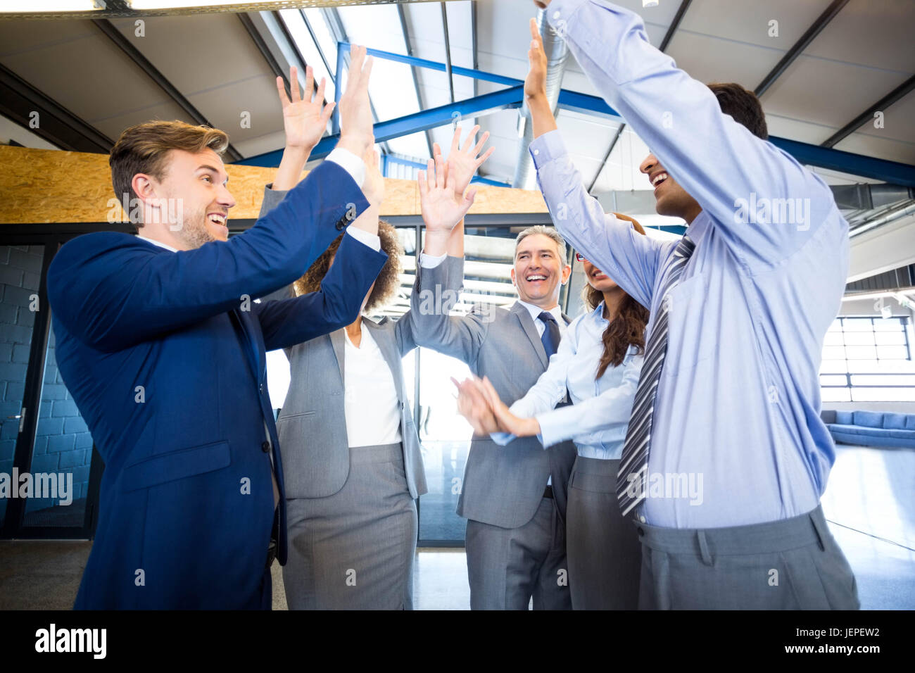 Happy business team high fiving Stock Photo - Alamy