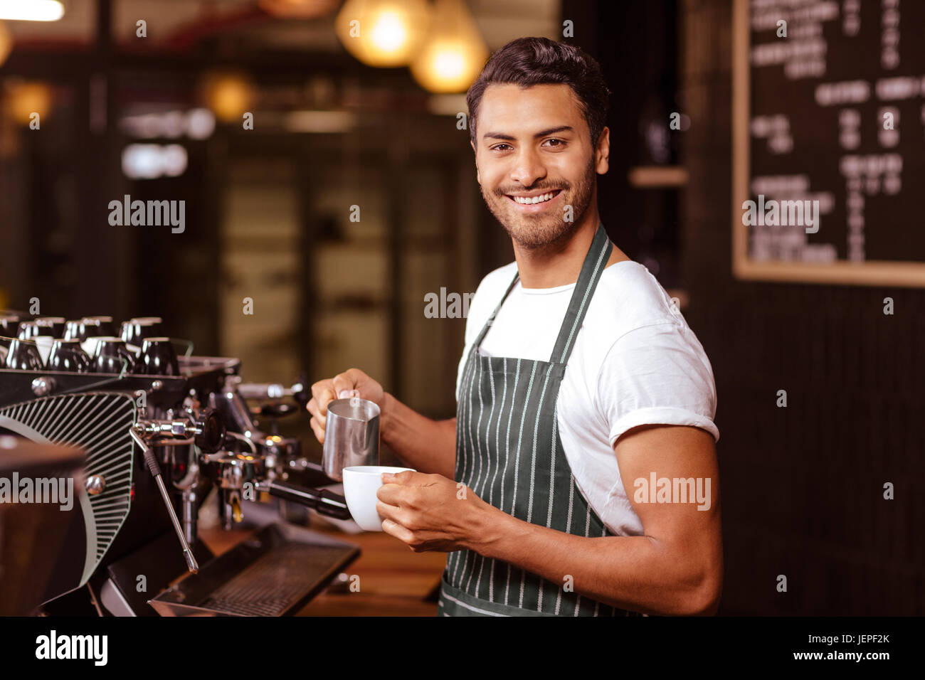 Handsome waiter adding milk to coffee Stock Photo - Alamy