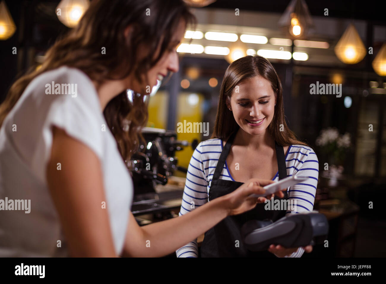 Smiling woman paying with smartphone Stock Photo - Alamy
