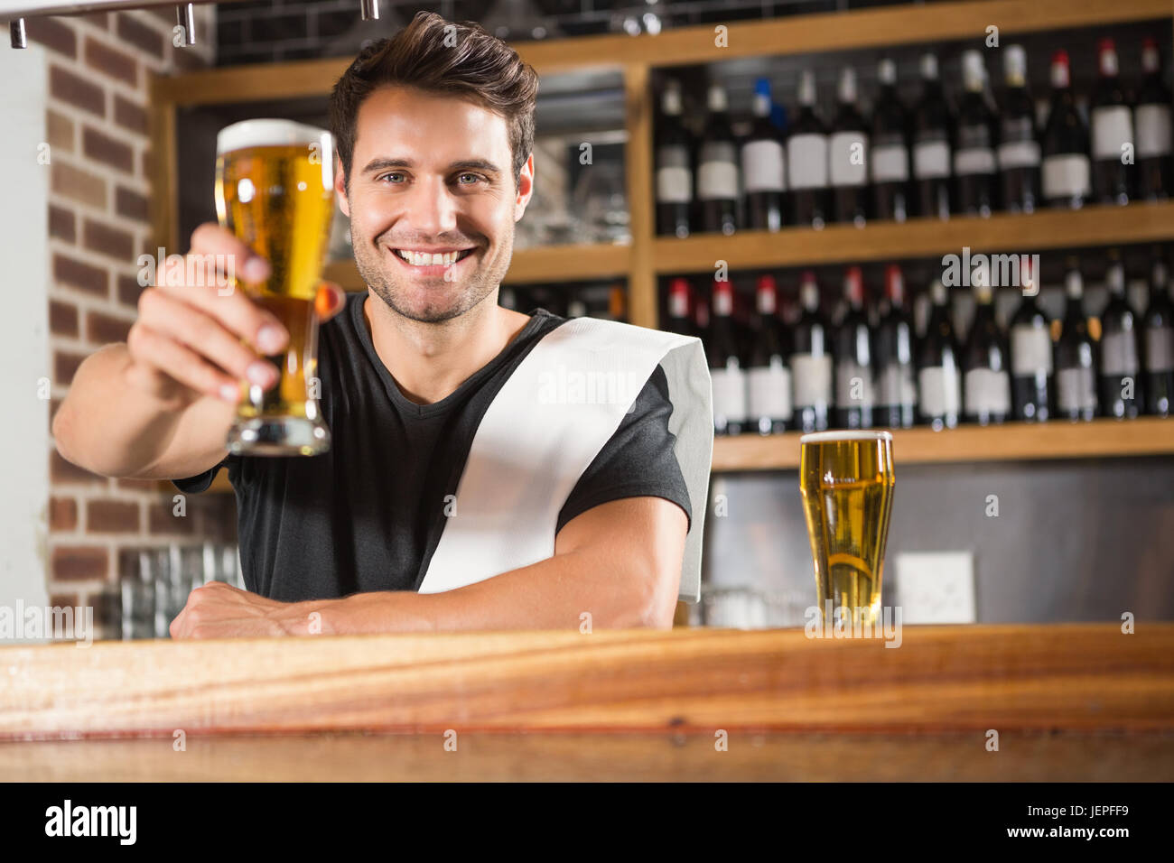 Handsome barman holding a pint of beer Stock Photo - Alamy