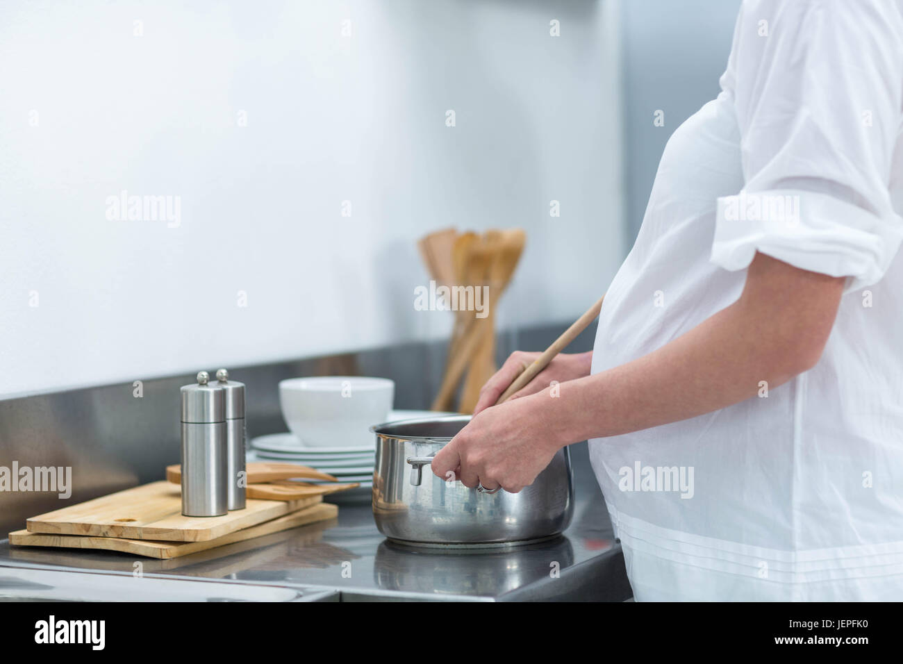 Pregnant woman busy in kitchen Stock Photo - Alamy
