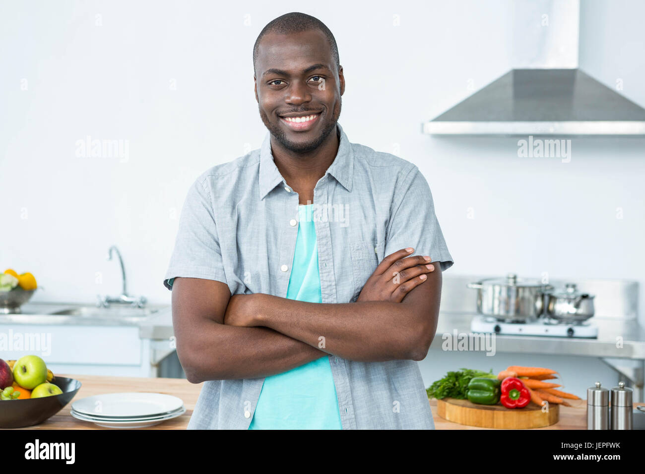 Man standing with arms crossed in kitchen Stock Photo - Alamy