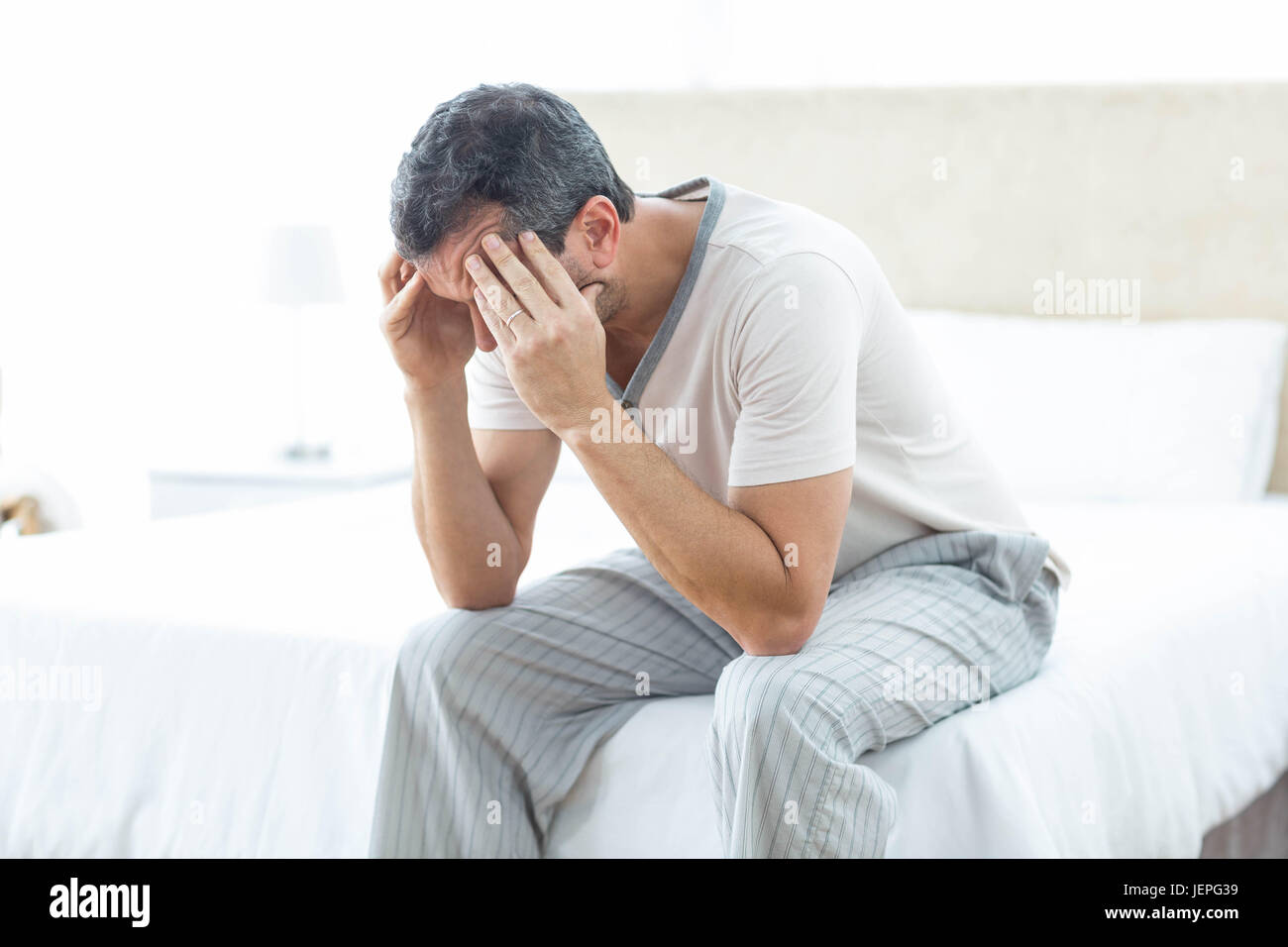 Worried man sitting on bed Stock Photo - Alamy