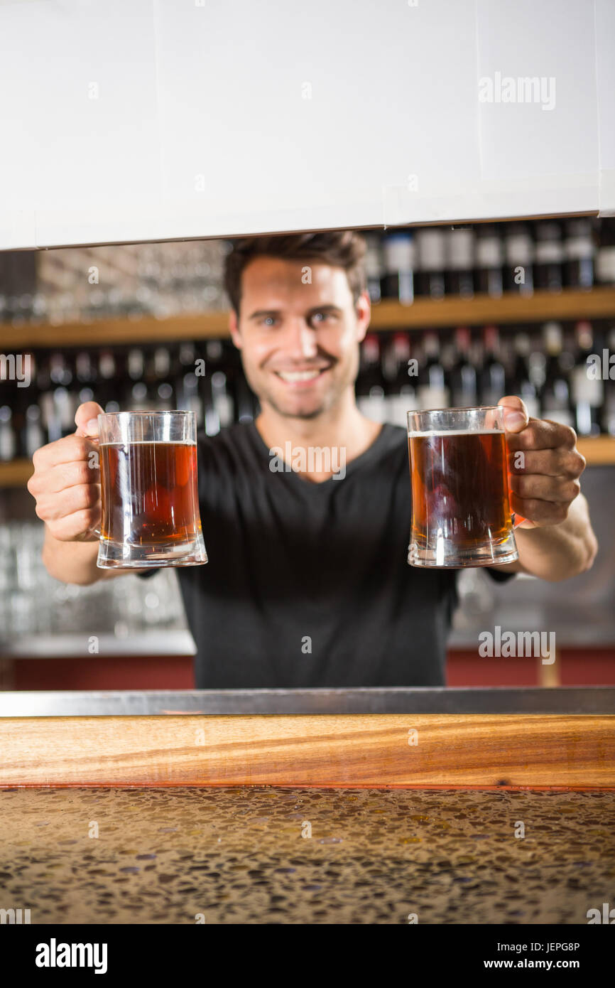 Handsome barman holding a pint of beer Stock Photo - Alamy