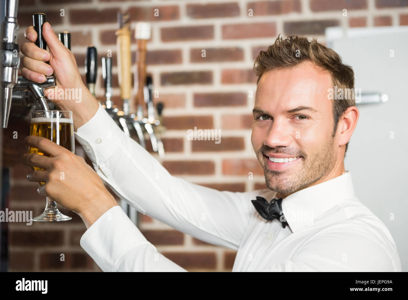 Handsome barman pouring a pint of beer Stock Photo - Alamy