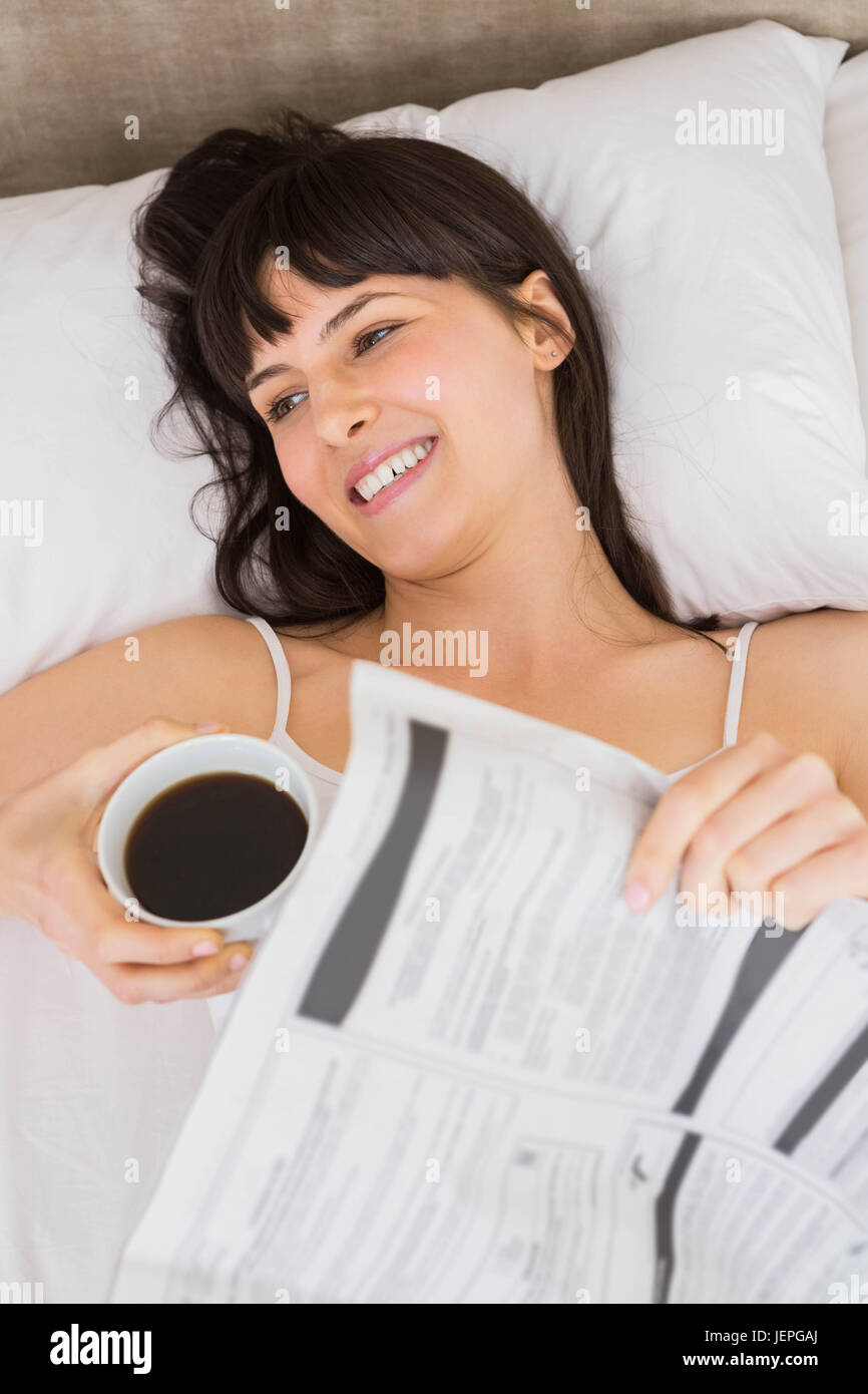 Woman lying on bed with cup of coffee Stock Photo - Alamy