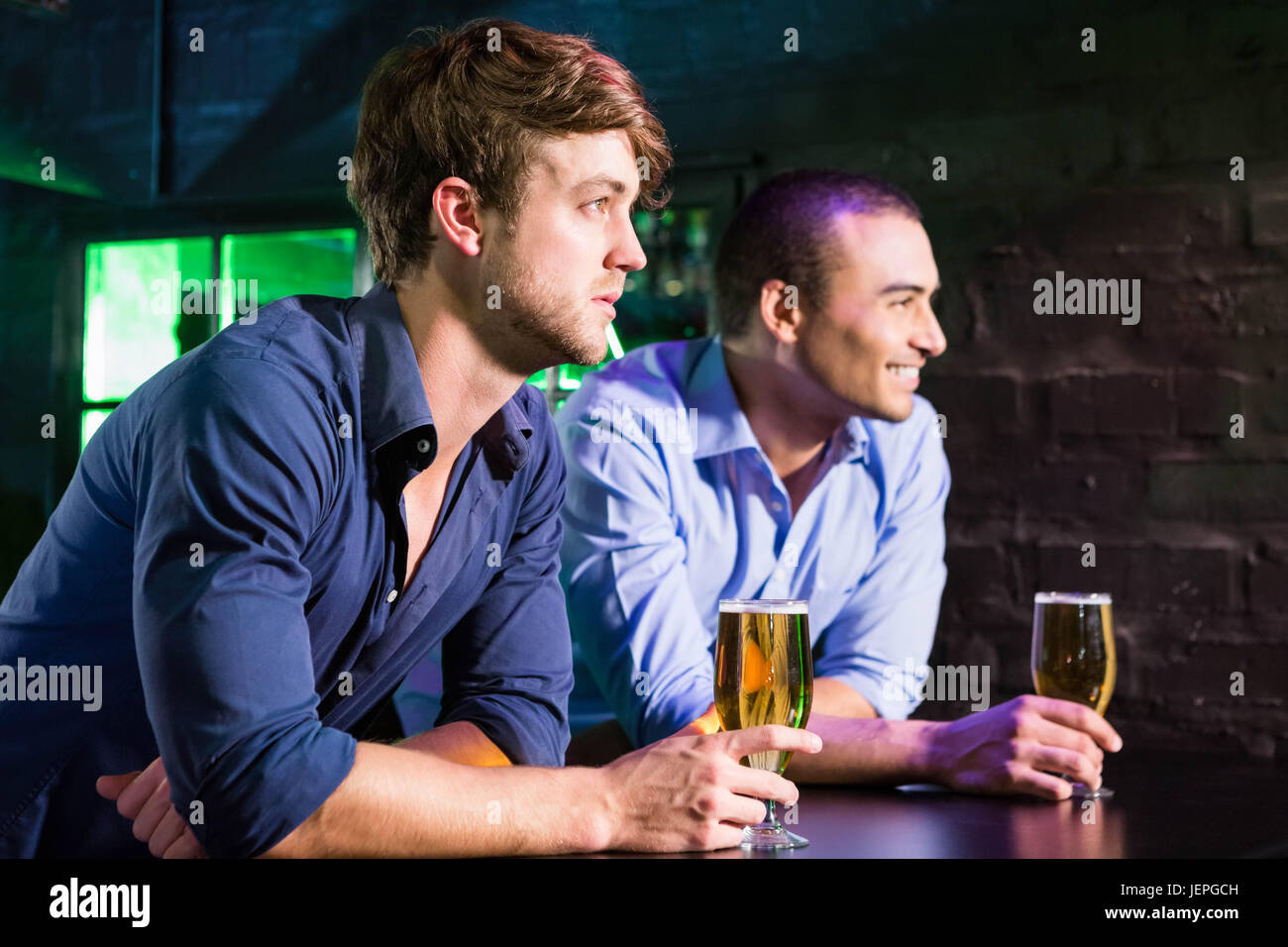 Two men having beer at bar counter Stock Photo - Alamy